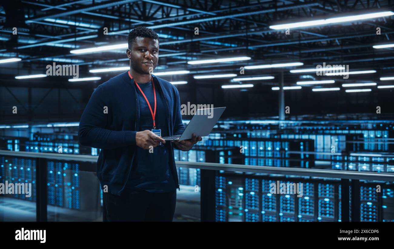 Portrait of a Data Center Engineer Using Laptop Computer. Server Room Specialist Facility with ...