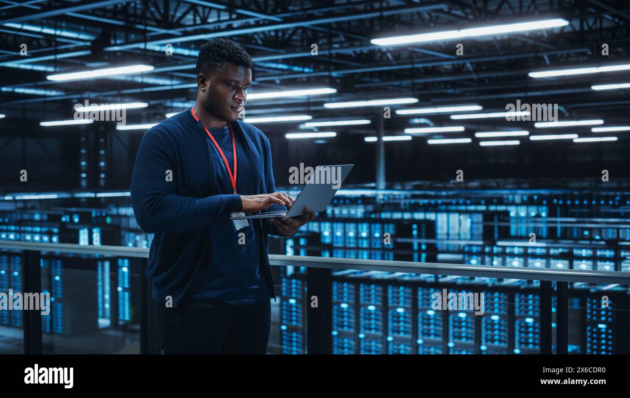 Portrait of a Data Center Engineer Using Laptop Computer. Server Room Specialist Facility with ...