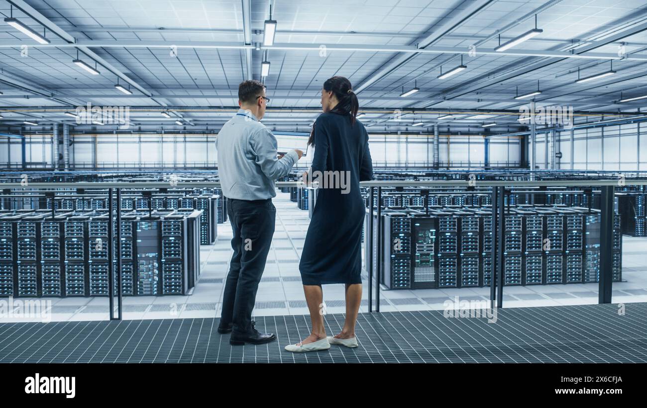 Data Center Female System Administrator and Male IT Specialist Talk, Use Laptop. Information ...