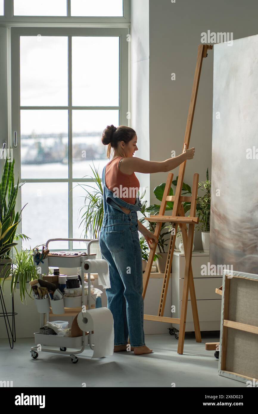 Inspired woman artist preparing easel before work painting process in ...