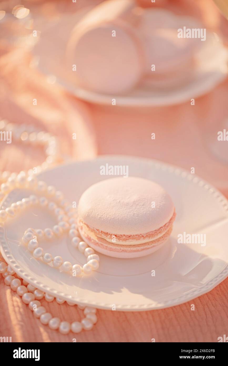 Macarons peach fuzz shade and natural pearls on a saucer. Color concept ...