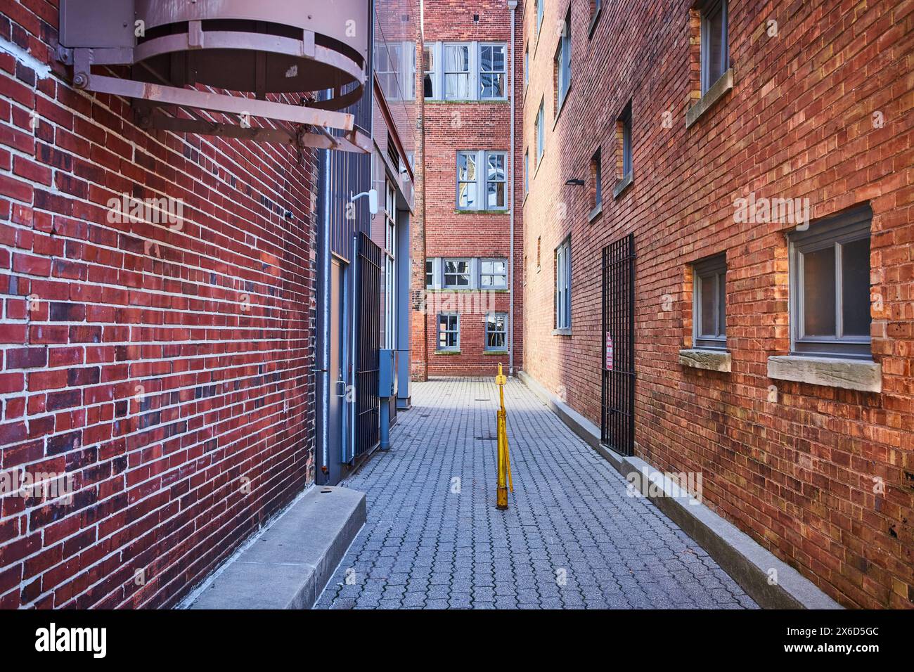 Urban Alleyway with Fire Escape and Barred Windows, Ground Level View ...