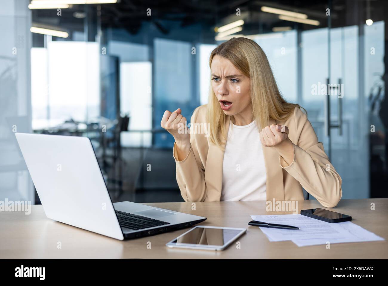 Businesswoman expressing frustration while working on laptop in a ...