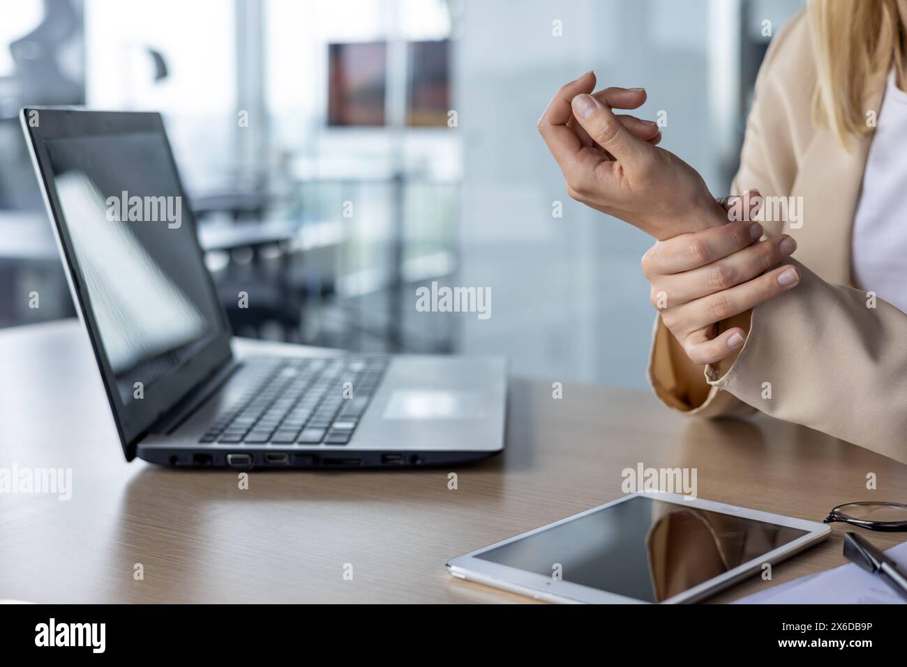 Businesswoman experiencing wrist pain while working on laptop in a ...