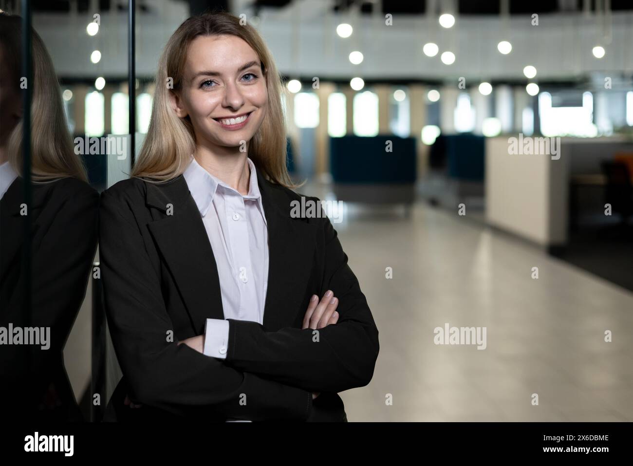 A professional young woman stands confidently in an office setting ...