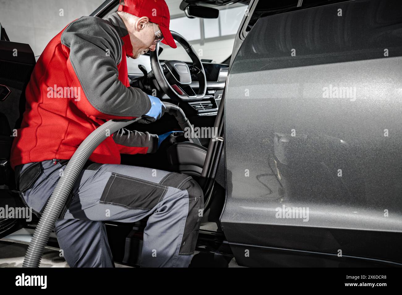 Automotive worker using vacuum to clean modern car interior Stock Photo ...