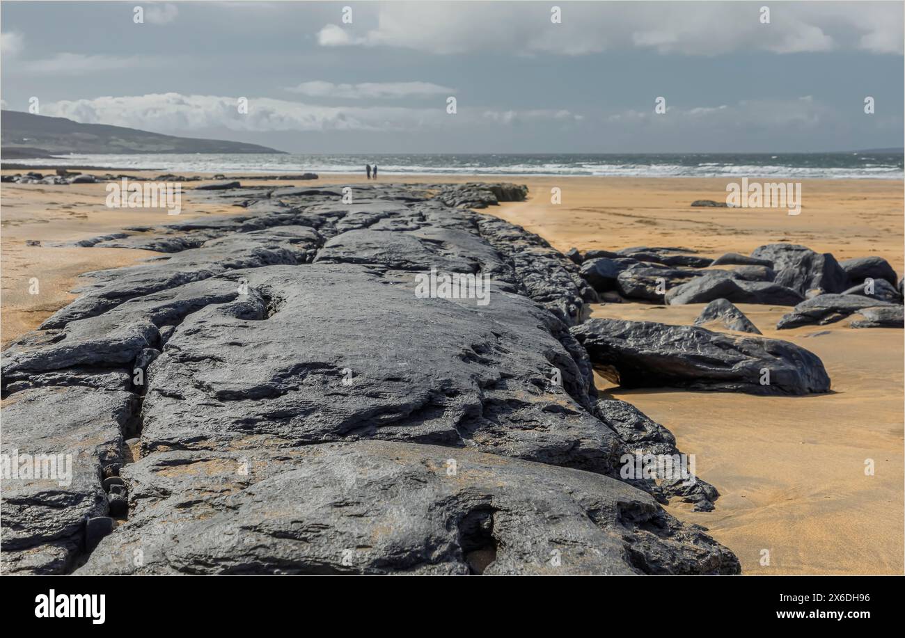 Strange dark stone limestone path on a beach leading your eye to two ...