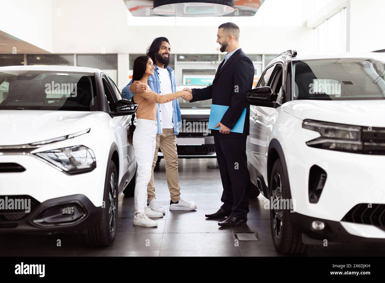 Professional Car Salesman Handshaking With Happy Customers in ...