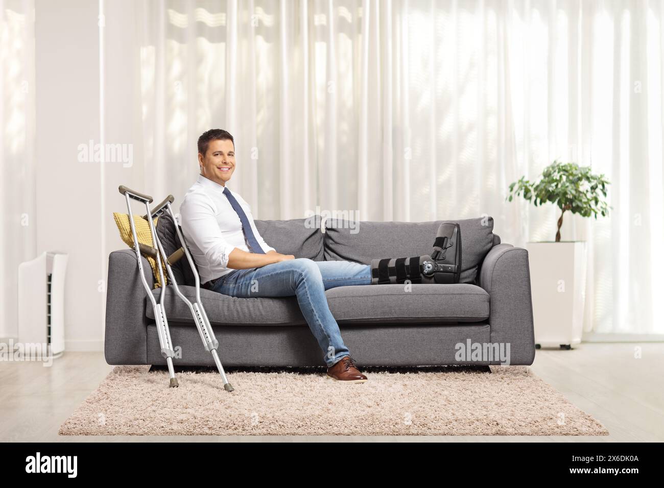 Man with a foot injury and leg brace sitting on a sofa at home Stock ...