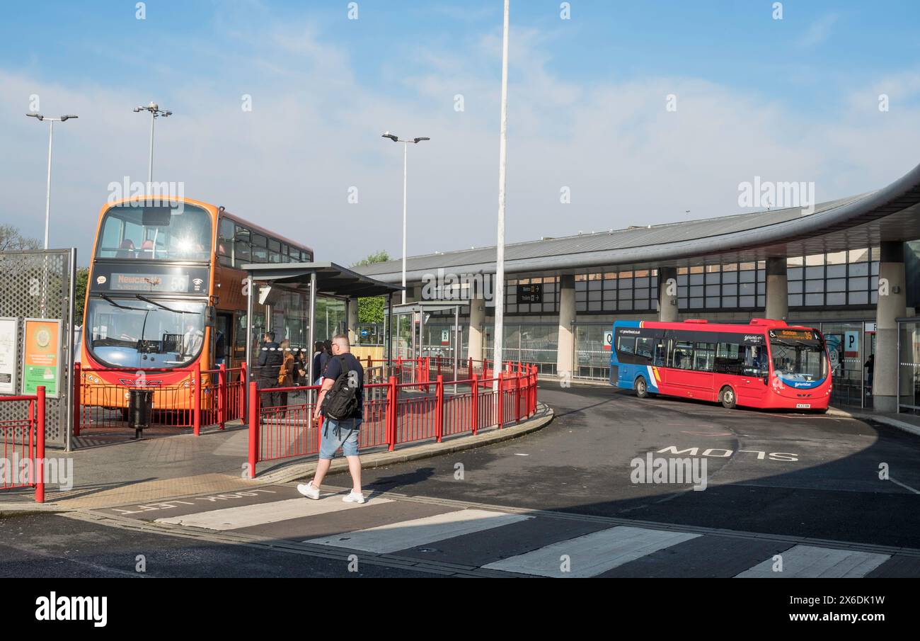 Man crossing road to board a bus in Sunderland bus station, England, UK ...