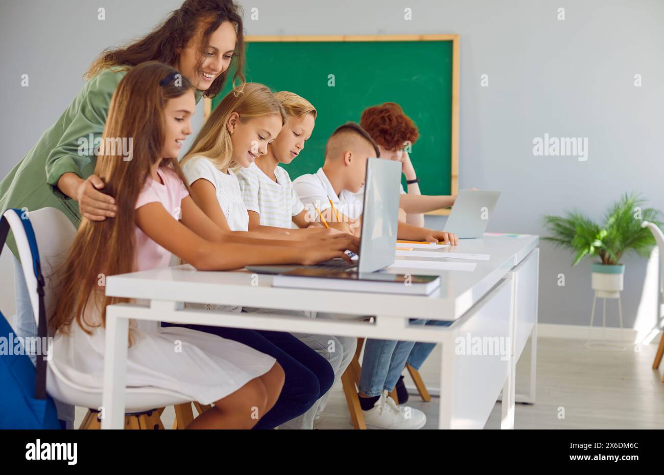 Happy Teacher Assisting Students with Teamwork in Classroom Stock Photo ...
