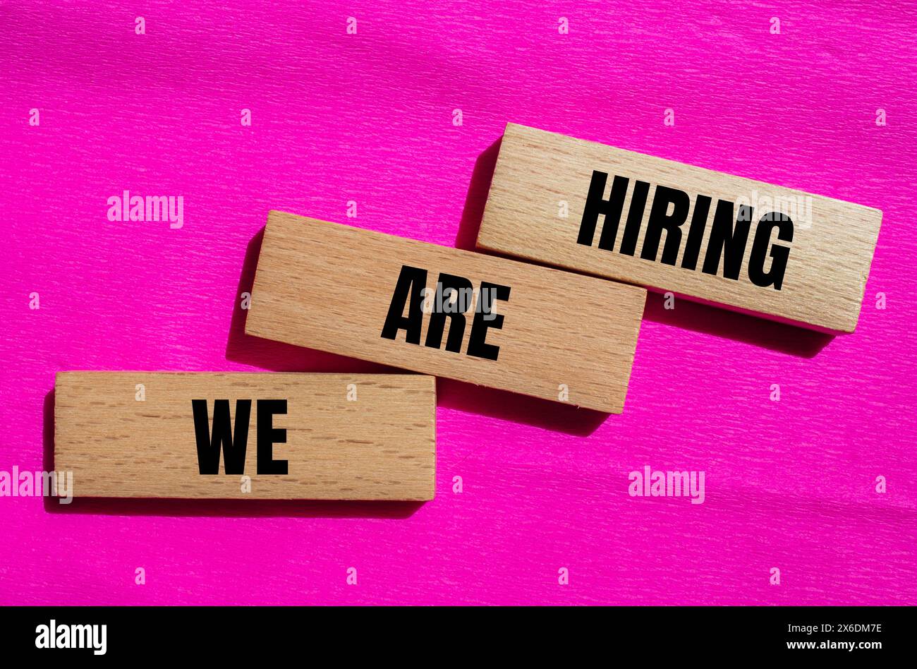 We are hiring words written on wooden blocks with pink background ...