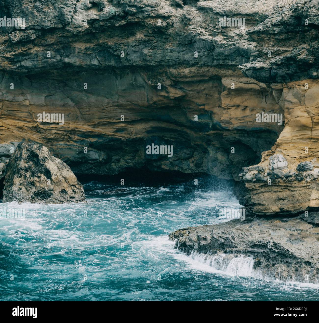 Rocky coastal cave with turquoise waters and rugged cliffs in ...