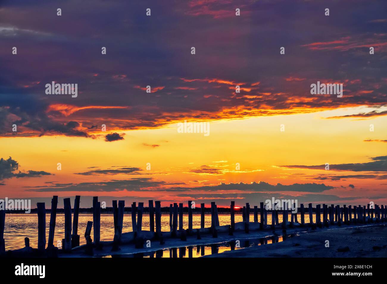 An old abandoned salina in the rays of the low sun. A stockade of logs ...