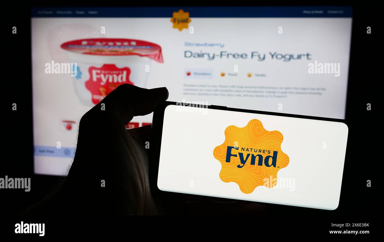 Person holding mobile phone with logo of American company The Fyn­der ...