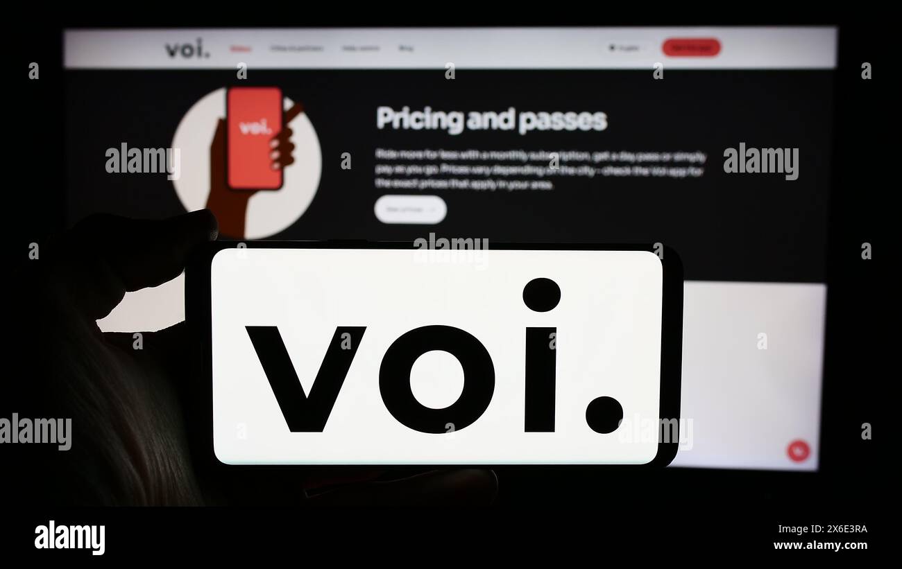Person holding mobile phone with logo of Swedish electric scooter company Voi Technology AB in ...