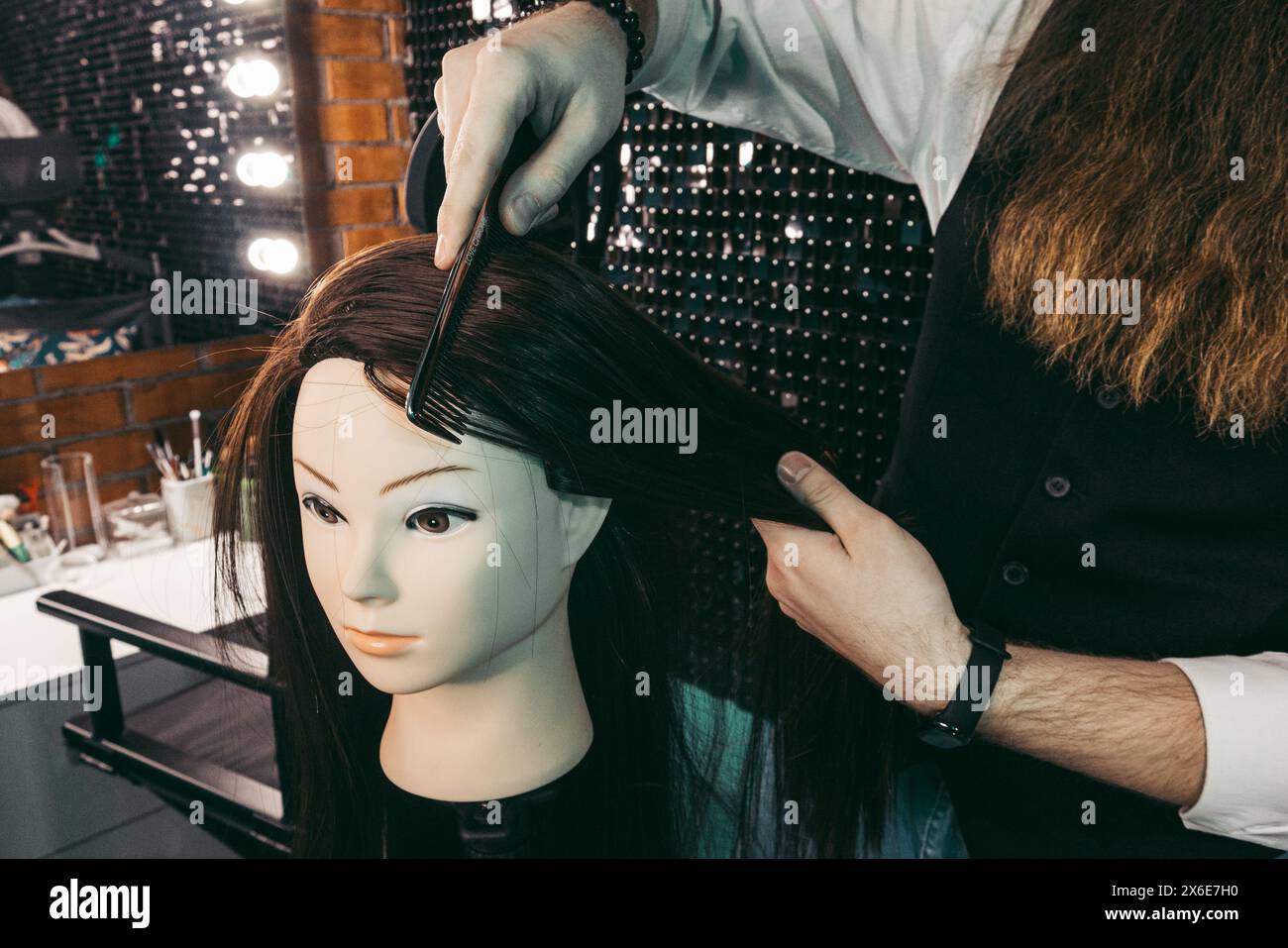 Hairdresser combing practice on mannequin .Man young hairdresser ...