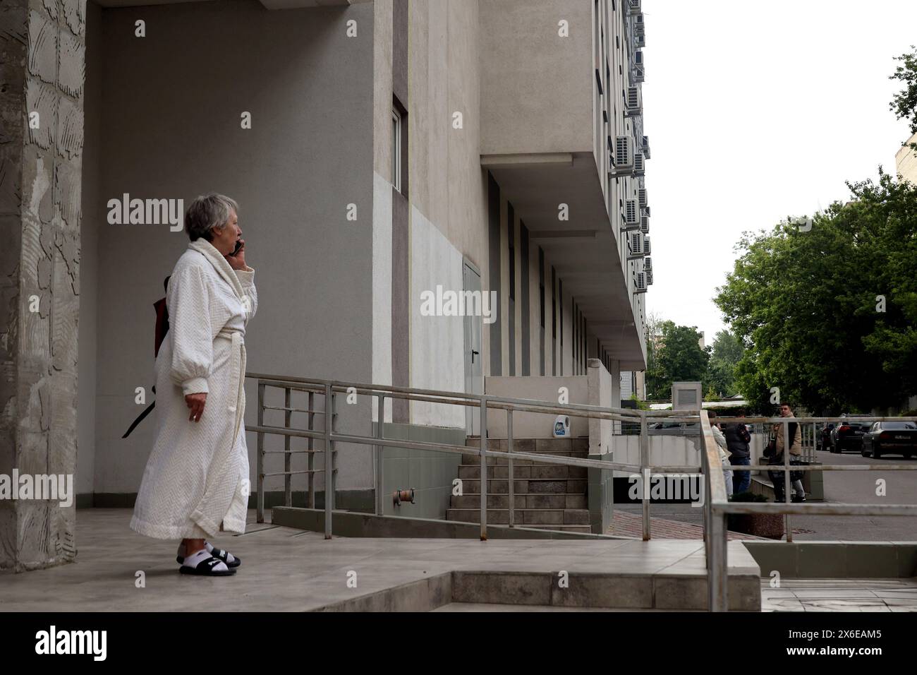KHARKIV, UKRAINE - MAY 14, 2024 - A woman in a dressing gown outside a ...