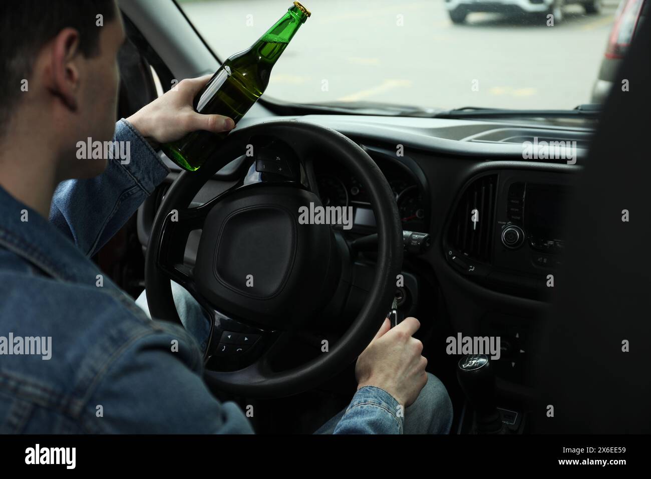 Man with bottle of beer driving car, closeup. Don't drink and drive ...