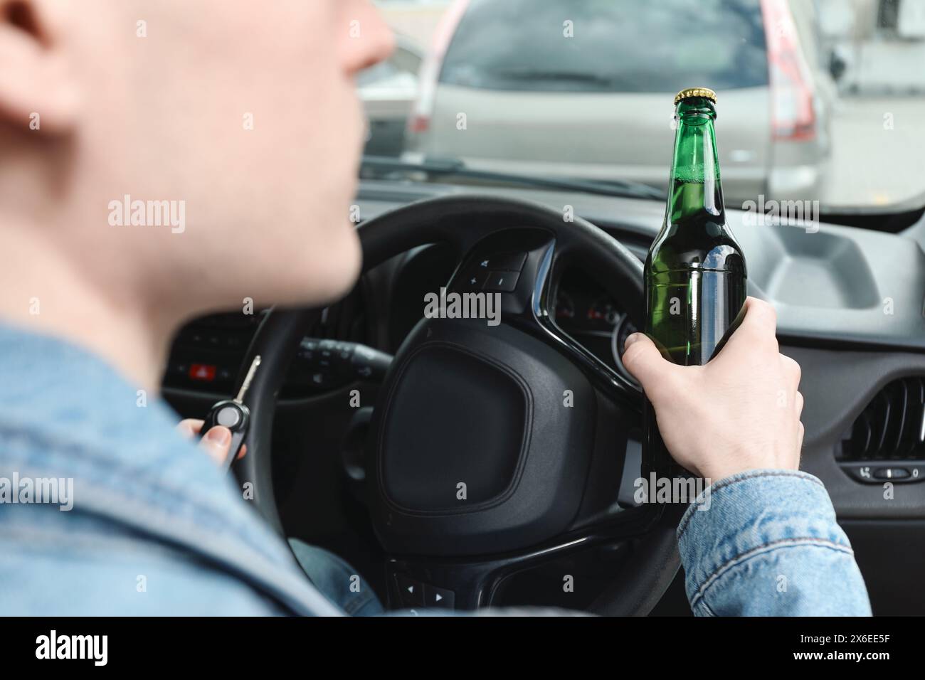 Man with bottle of beer driving car, closeup. Don't drink and drive ...