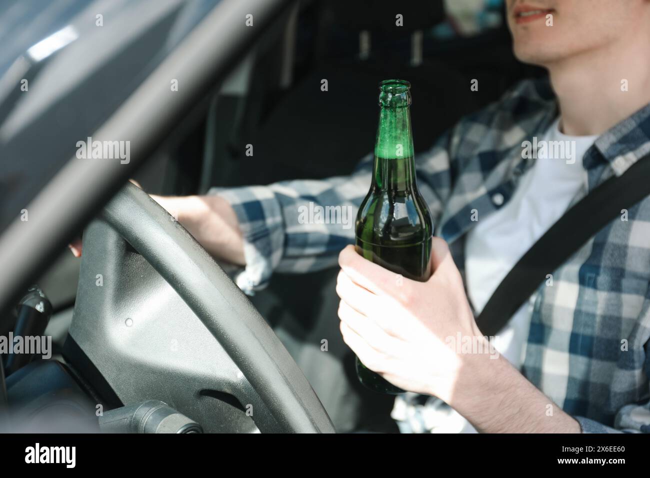 Man with bottle of beer driving car, closeup. Don't drink and drive ...