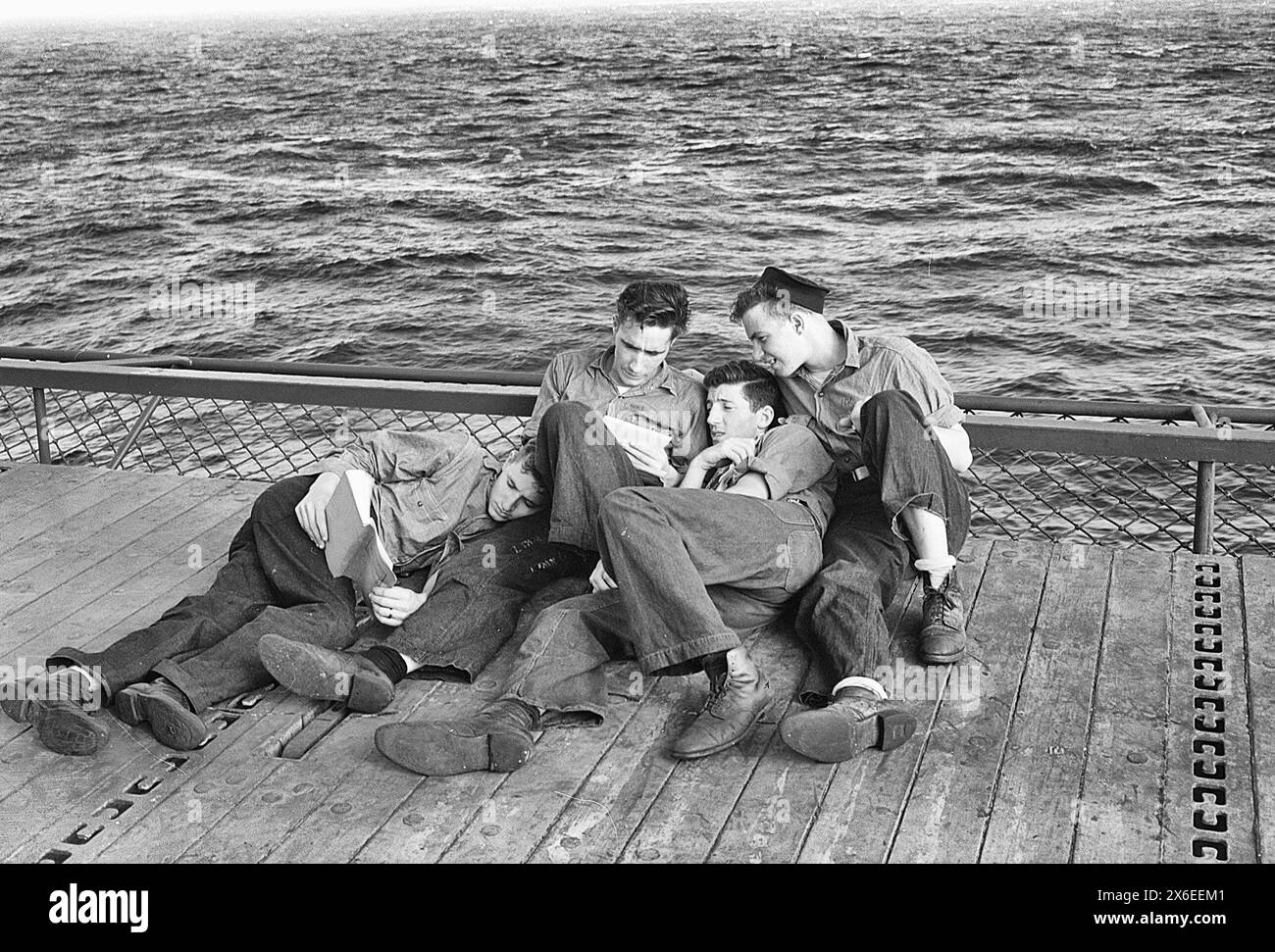 Enlisted men reading on edge of elevator aboard USS Lexington (CV-16 ...