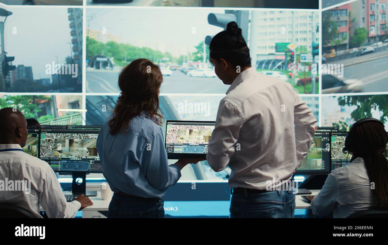 Diverse team following city traffic on a display in monitoring room ...