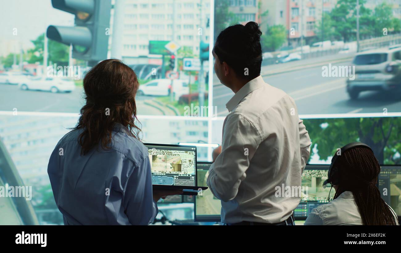 Diverse team following city traffic on a display in monitoring room ...