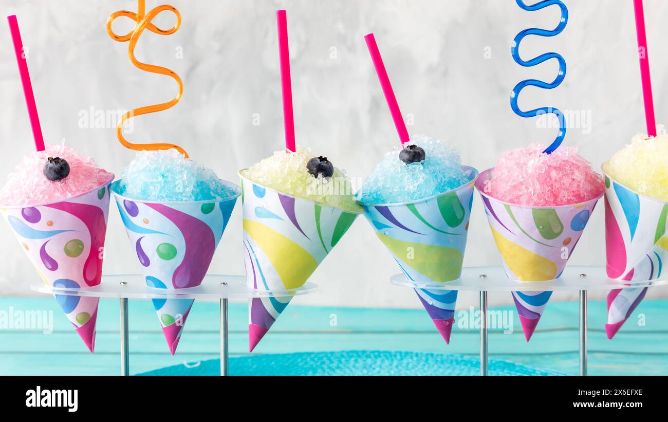 A row of flavoured snow cones with silly straws against a light ...