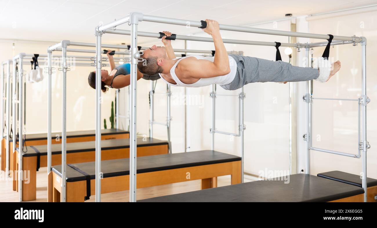 Man performing inverted hanging pull-ups on Pilates trapeze table Stock ...