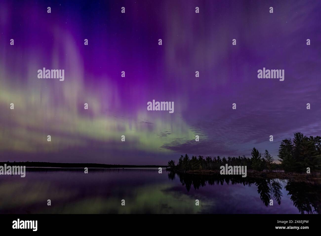 Northern lights erupt over a lake in Minnesota in a dark sky overhead ...