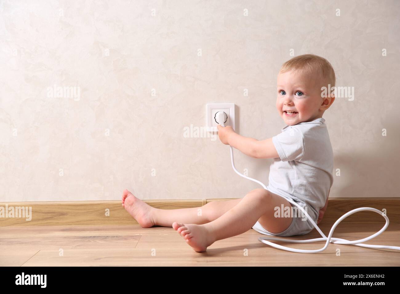 Little child playing with electrical socket and plug indoors, space for ...