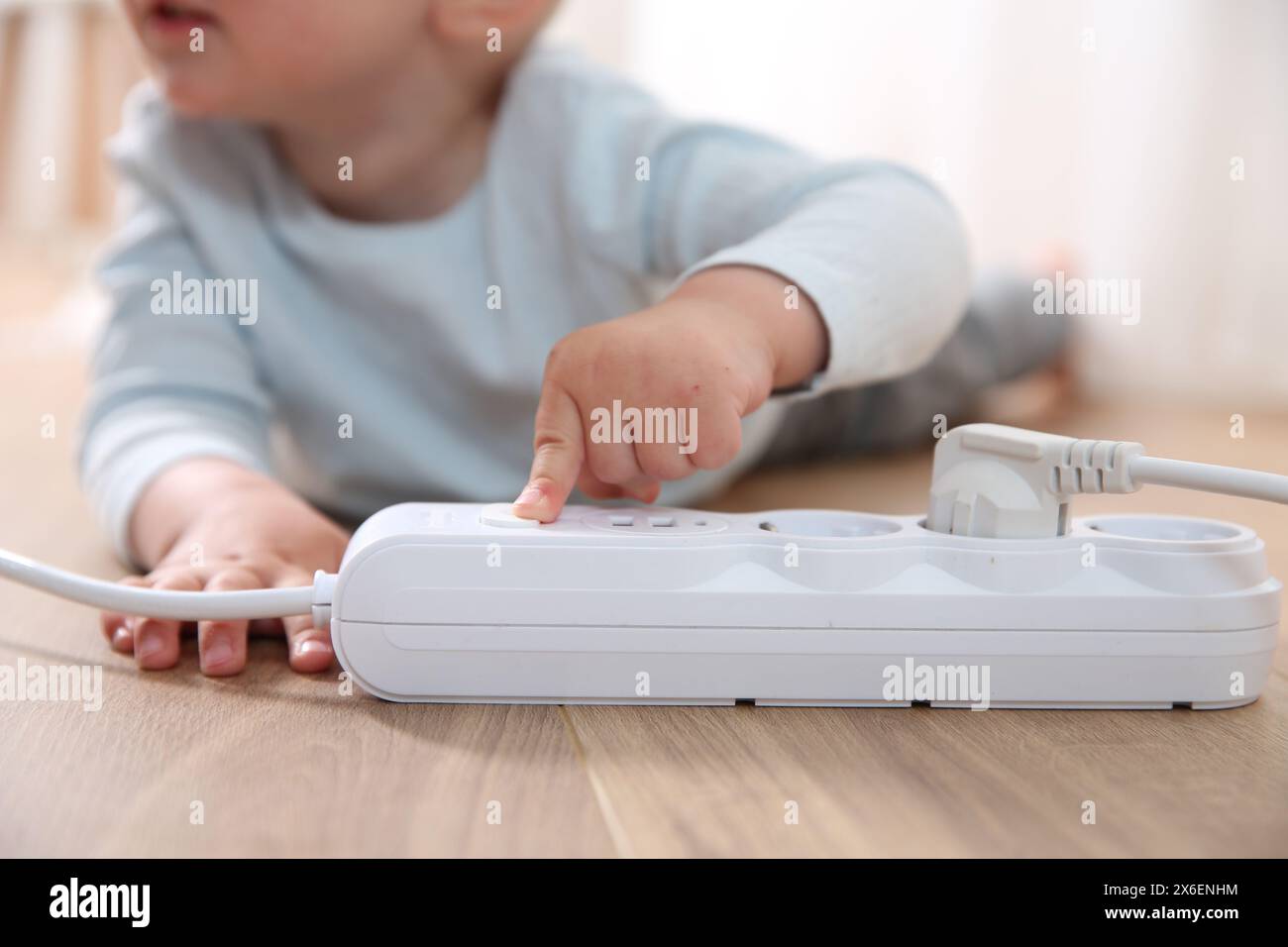 Little child playing with power strip on floor indoors, closeup ...