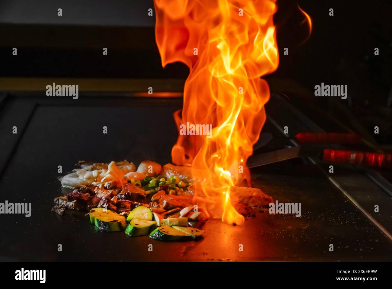 chef's hands with spatula over teppanyaki. cooking vegetables meat and ...