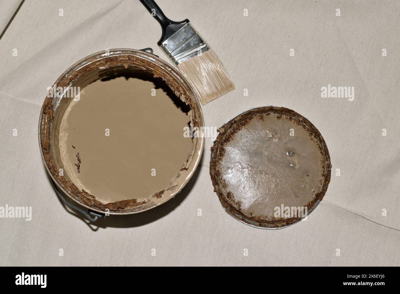 Rusted old metal paint tin with open lid paintbrush on drop cloth brown ...