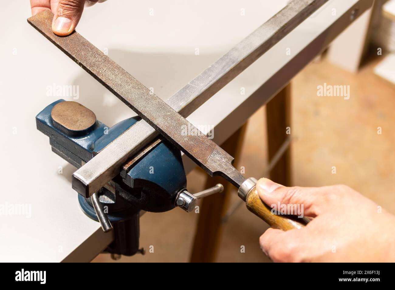 Man works with iron pipe or metallic aluminum file rasp gripped in vise ...