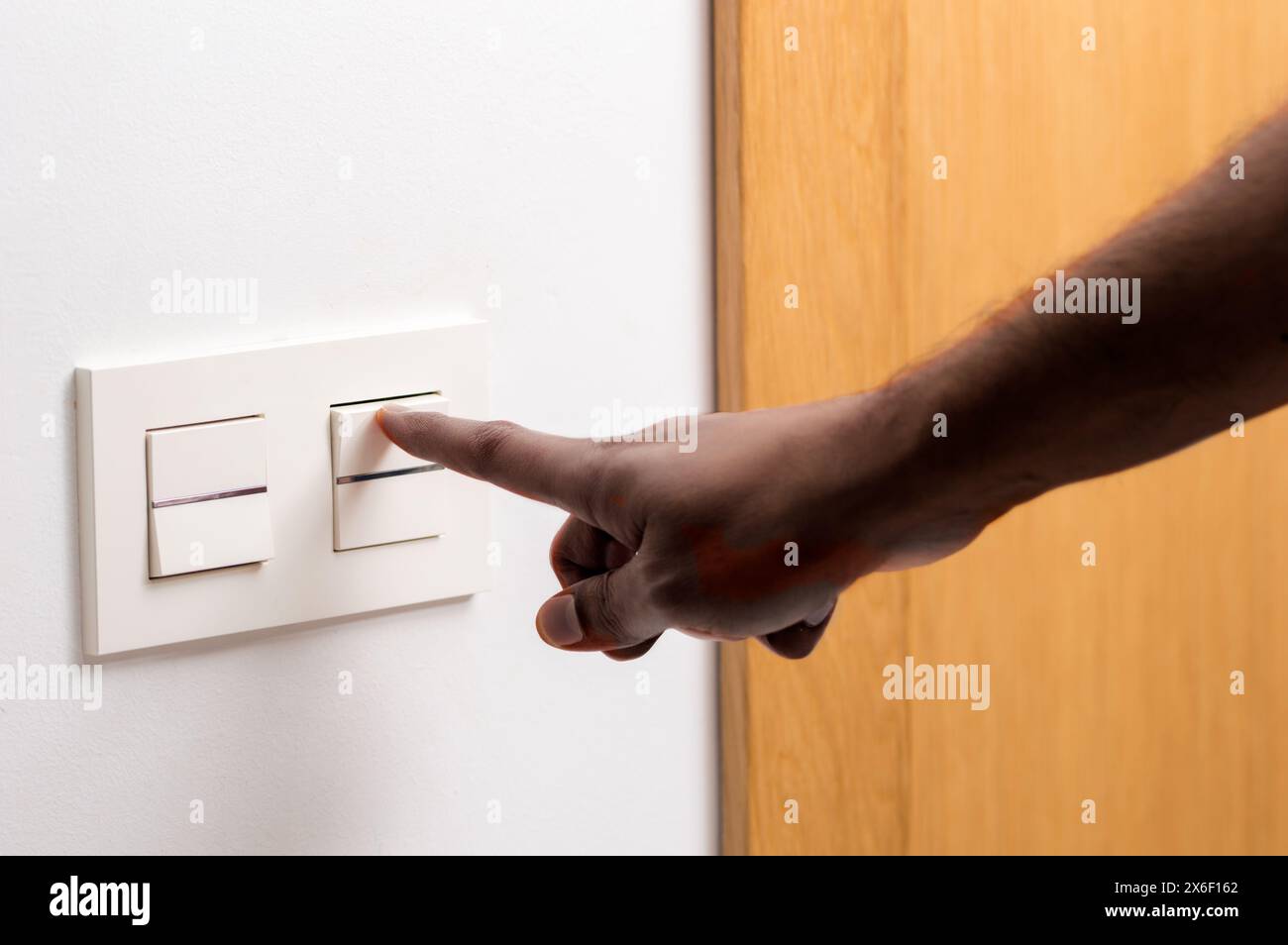Close up of man hand turning on the light with a wall switch at home ...