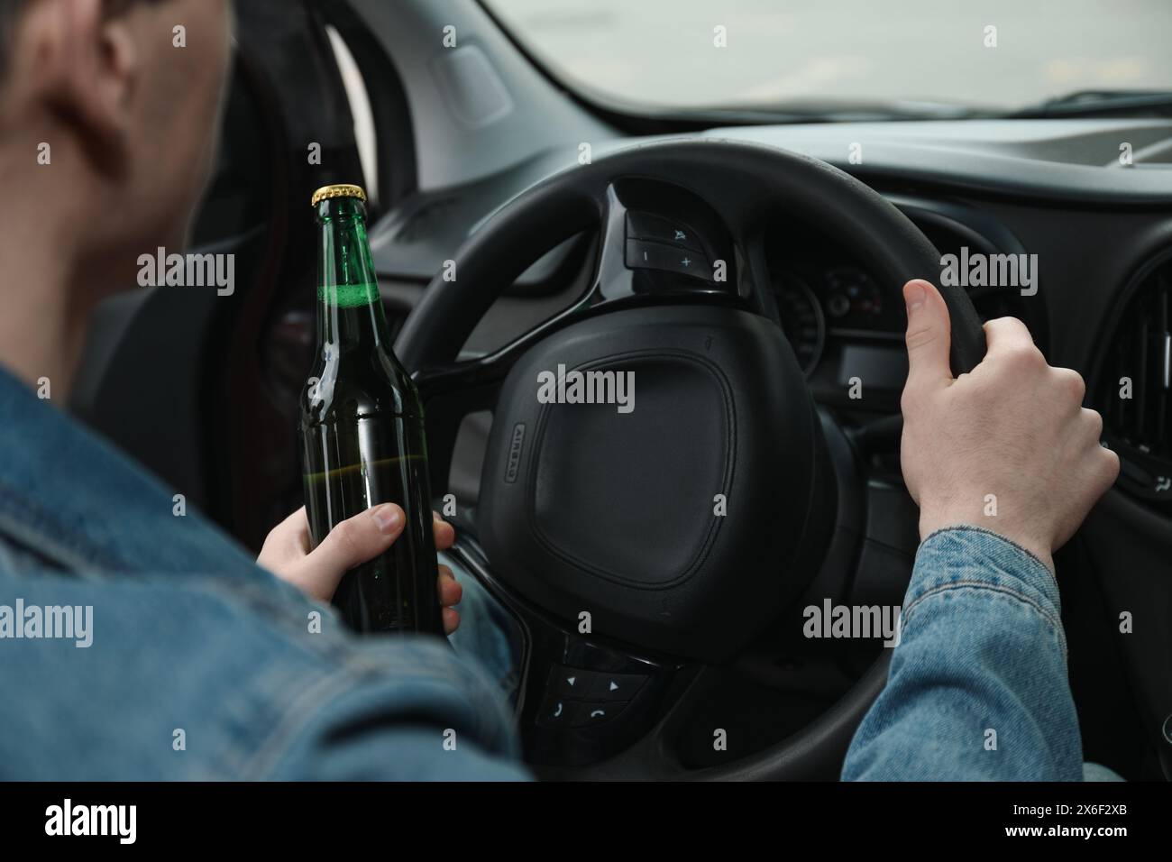 Man with bottle of beer driving car, closeup. Don't drink and drive ...