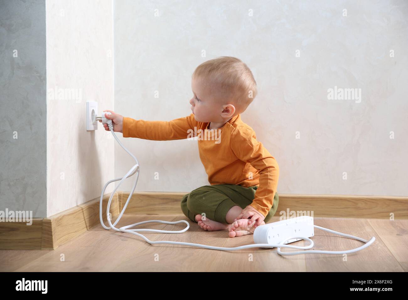 Little child playing with electrical socket and power strip plug at ...