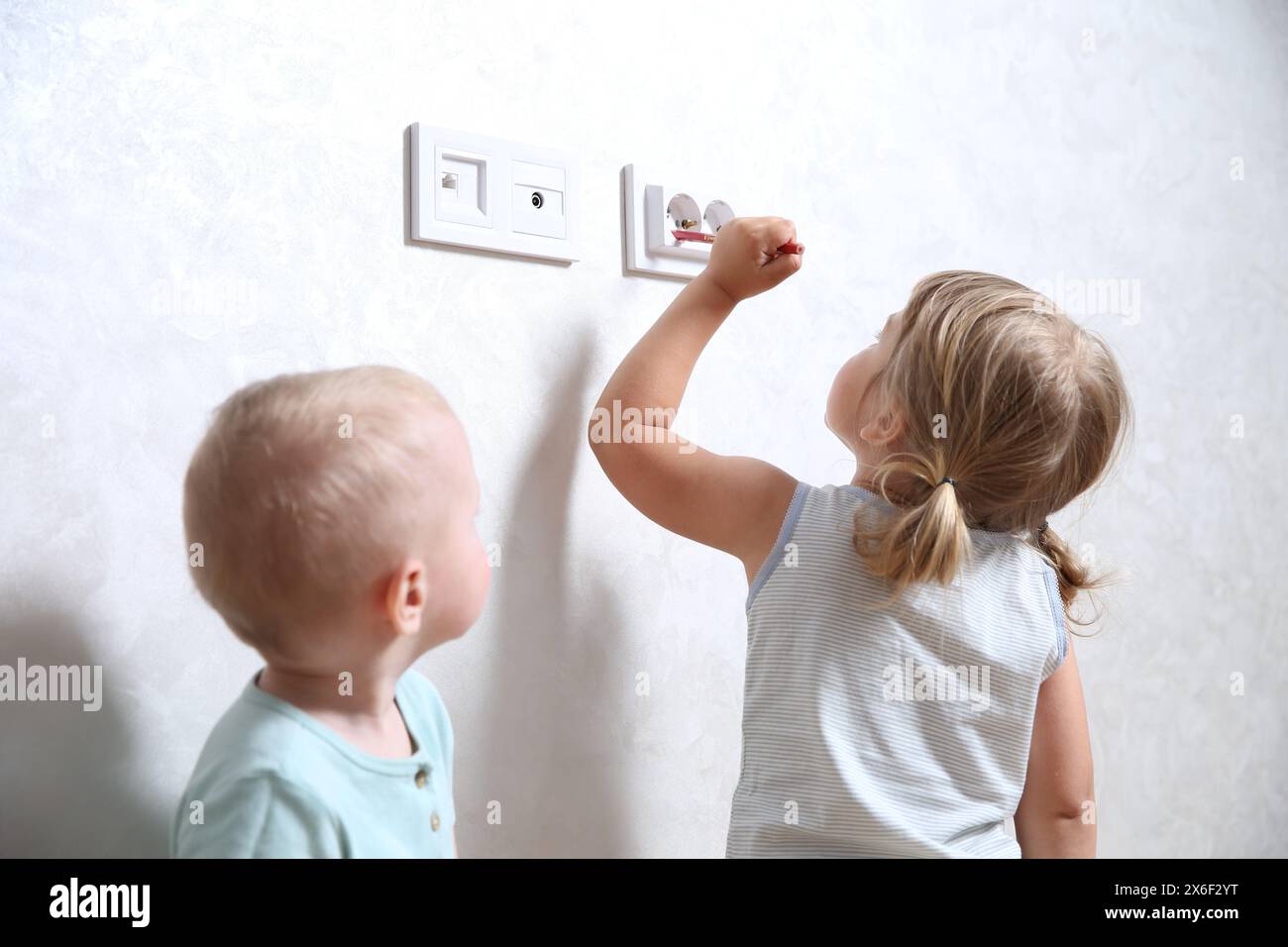Little children playing with electrical socket indoors. Dangerous ...