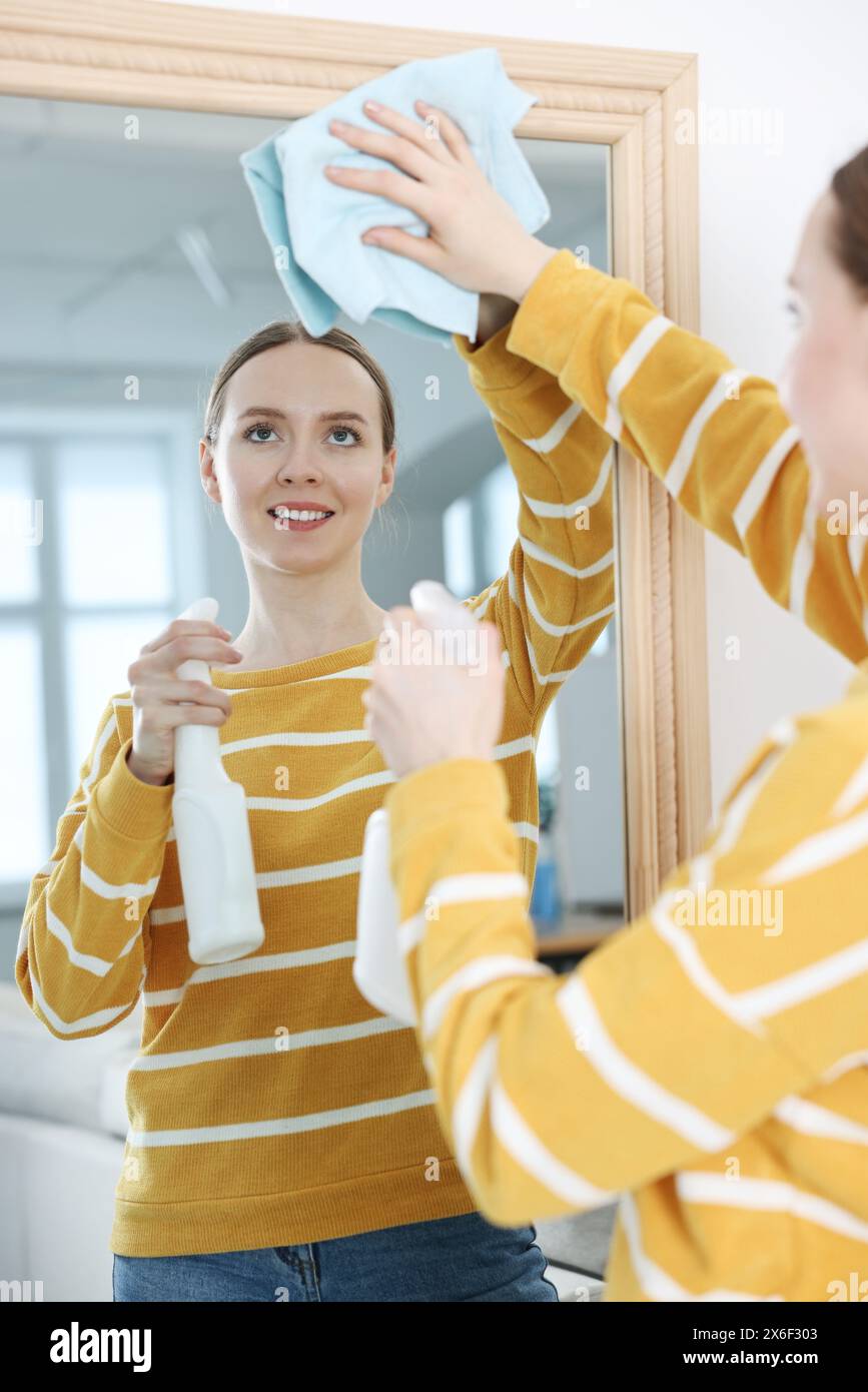 Woman with spay and rag cleaning mirror at home Stock Photo - Alamy