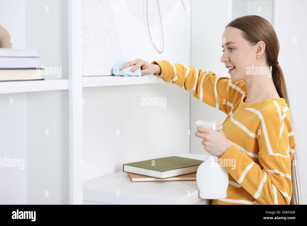 Woman with spay and rag cleaning shelf at home Stock Photo - Alamy