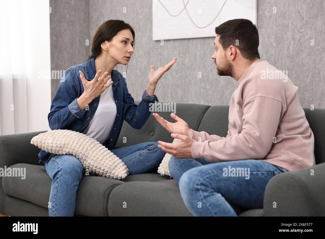 Emotional couple arguing on sofa indoors. Relationship problems Stock ...
