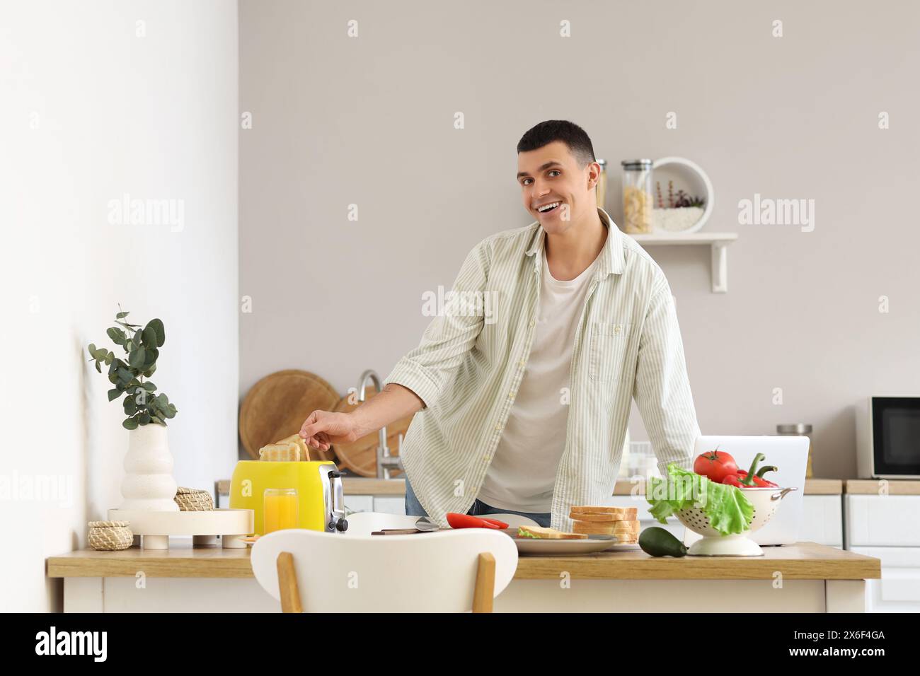 Young man making crispy toasts for sandwiches in kitchen Stock Photo ...