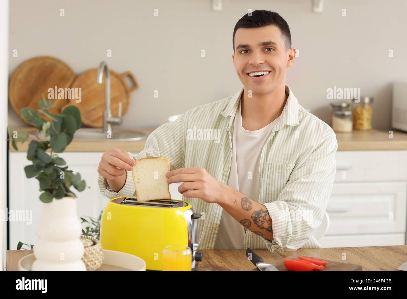 Young man making crispy toasts for sandwiches in kitchen Stock Photo ...