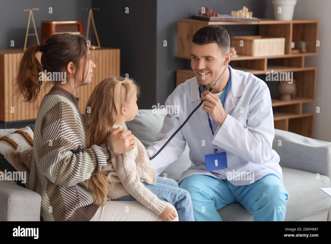 Male pediatrician with stethoscope examining little girl sitting on ...