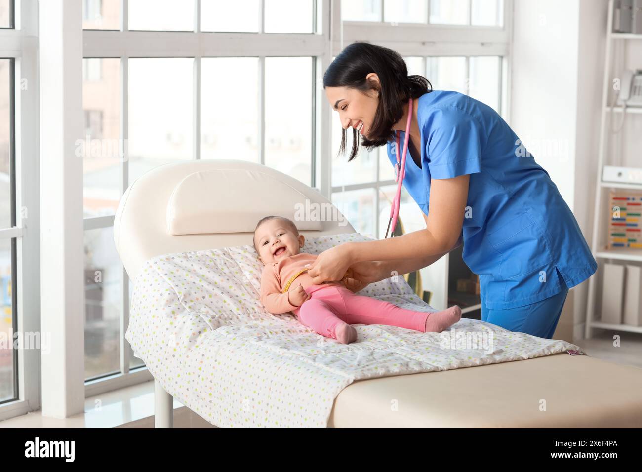 Female pediatrician measuring little baby's chest on couch in clinic ...