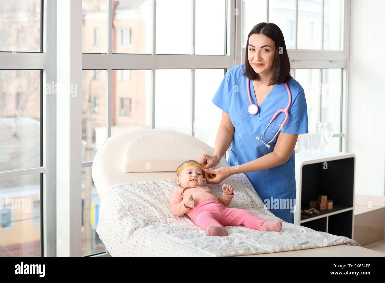 Female pediatrician measuring little baby's head on couch in clinic ...