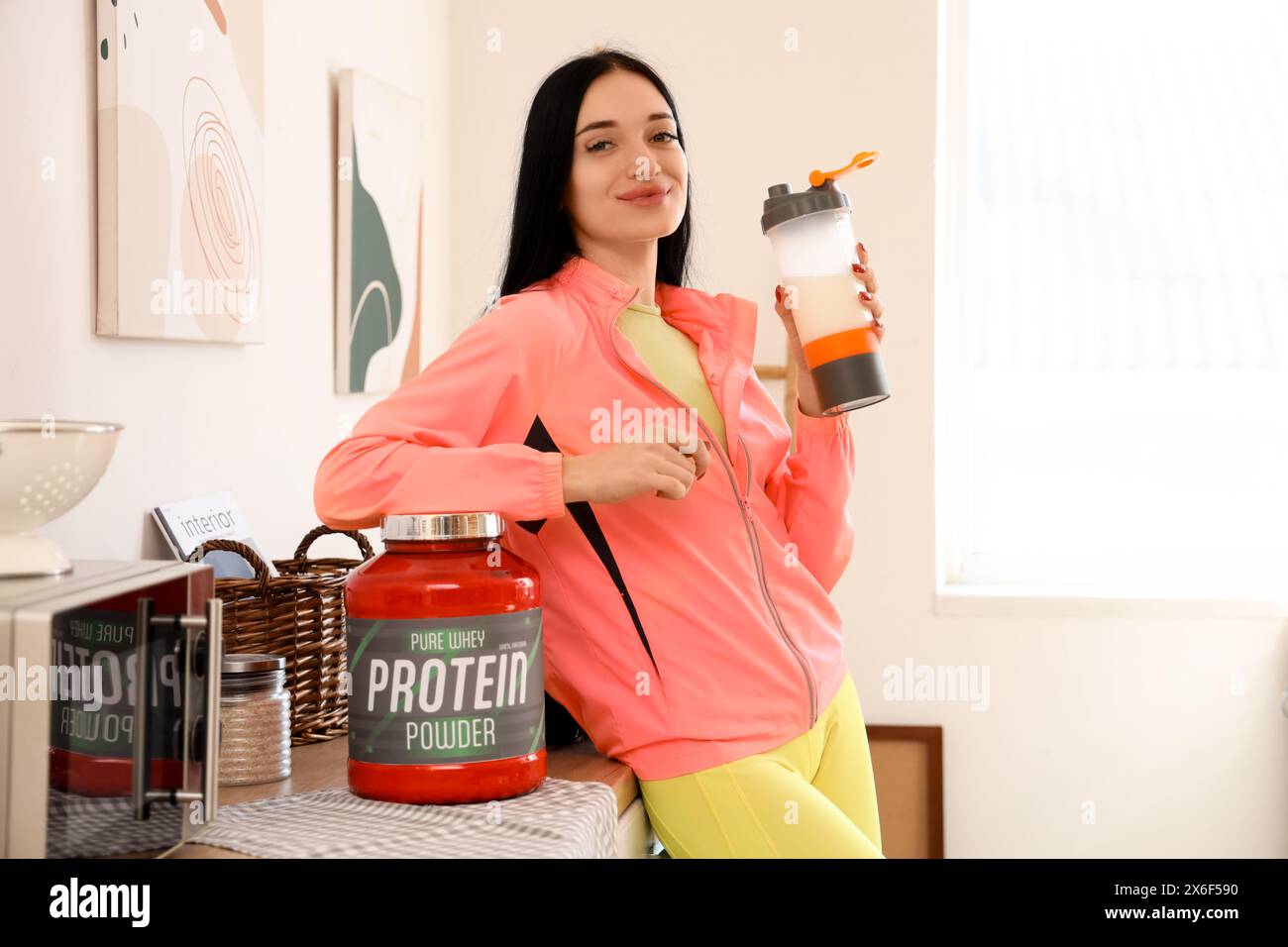 Sporty young woman with protein shake in kitchen Stock Photo - Alamy