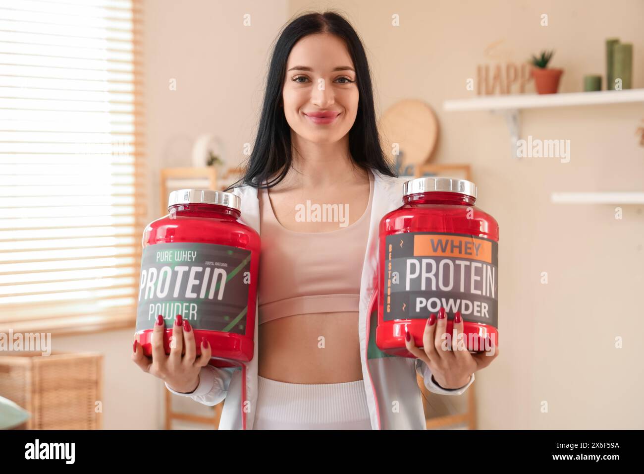 Sporty young woman with jars of protein powder at home Stock Photo - Alamy